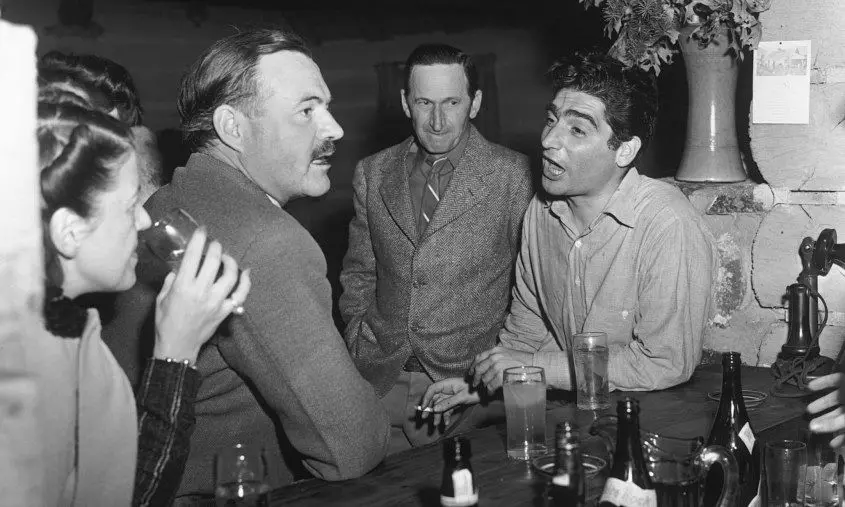 Hemingway drénken an enger Bar, schwätzt mam Fotojournalist Robert Capa am Joer 1940